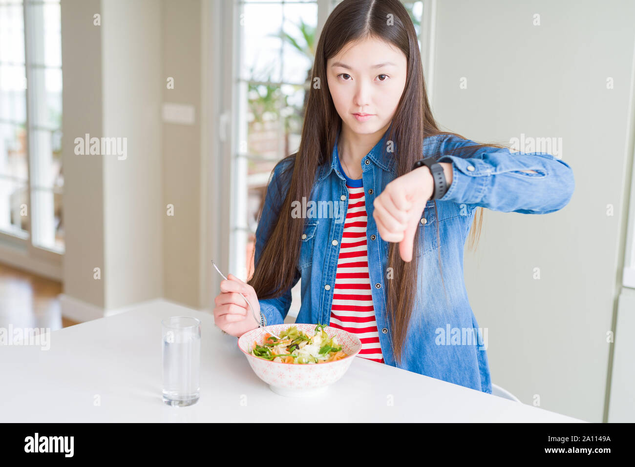 Beautiful Asian woman eating healthy pasta salad with angry face ...