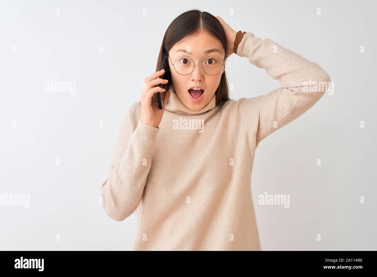 Young chinese woman talking on the smartphone over isolated white ...