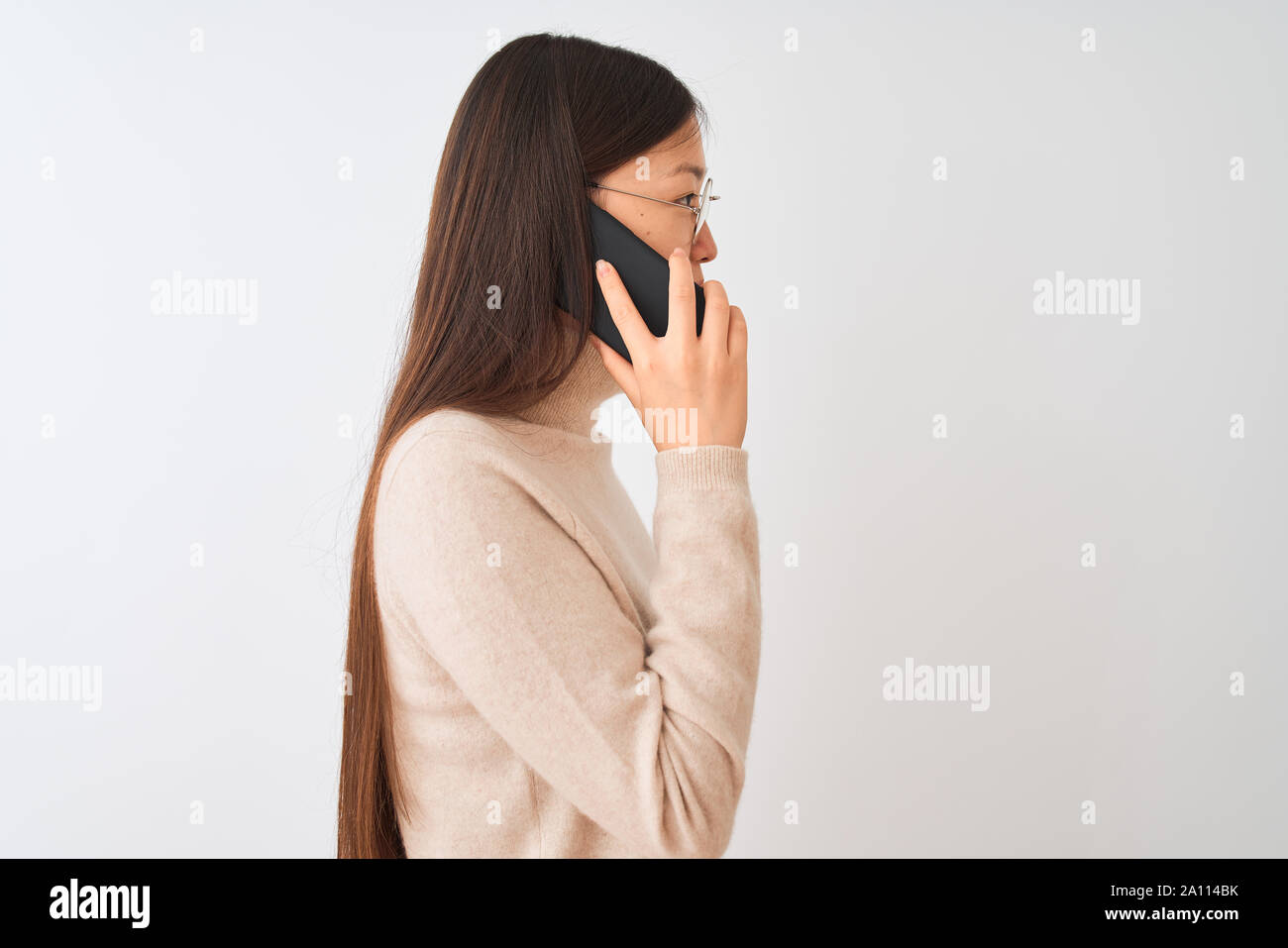 Young chinese woman talking on the smartphone over isolated white ...