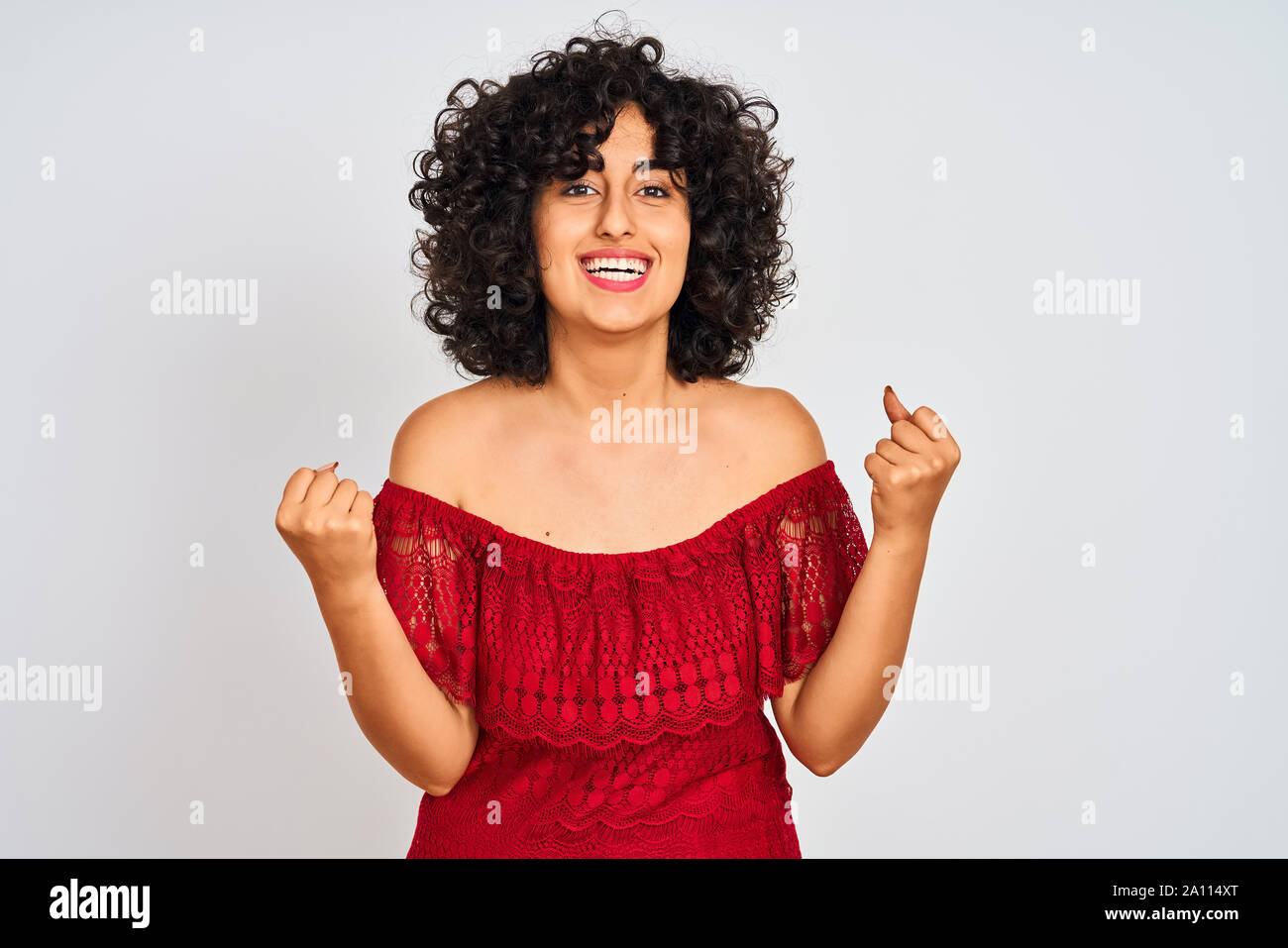 Young arab woman with curly hair wearing red dress standing over ...
