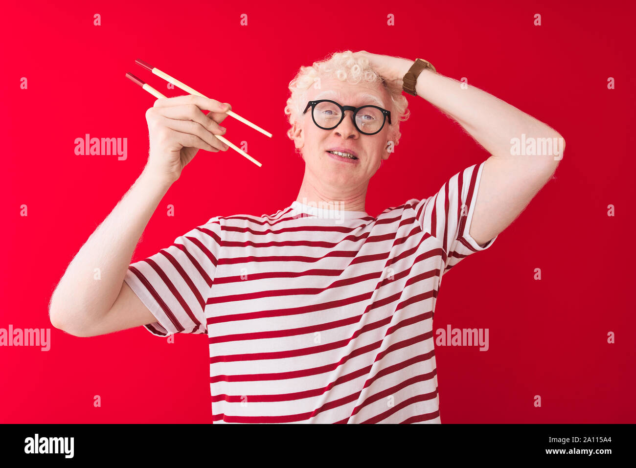 Young albino blond man holding chopsticks standing over isolated white ...