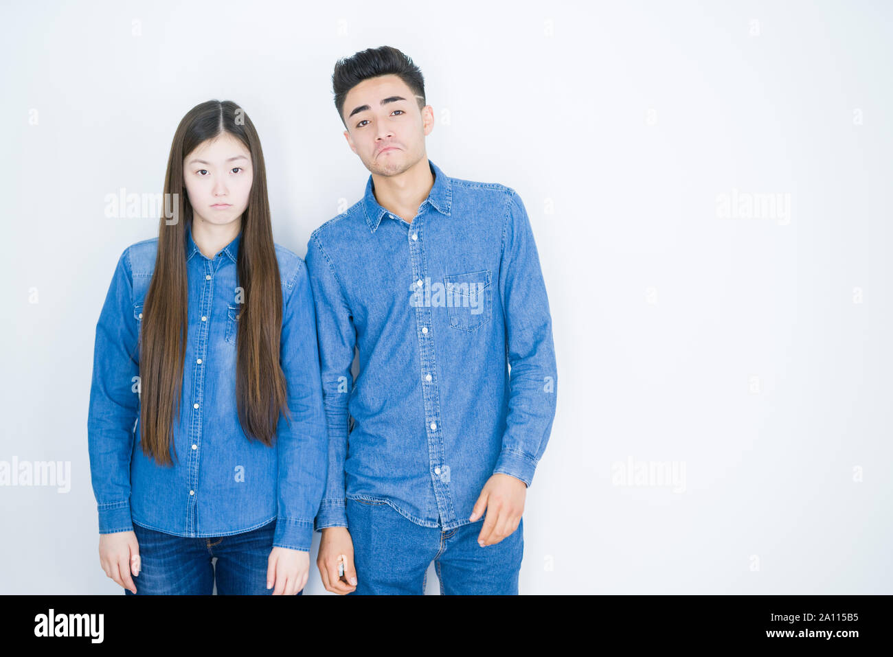 Beautiful young asian couple over white isolated background depressed ...