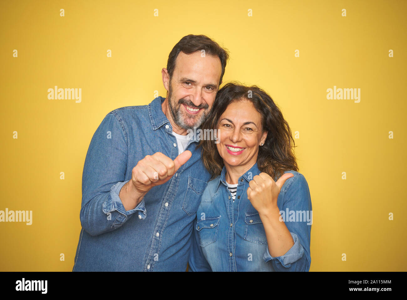 Beautiful middle age couple together standing over isolated yellow ...