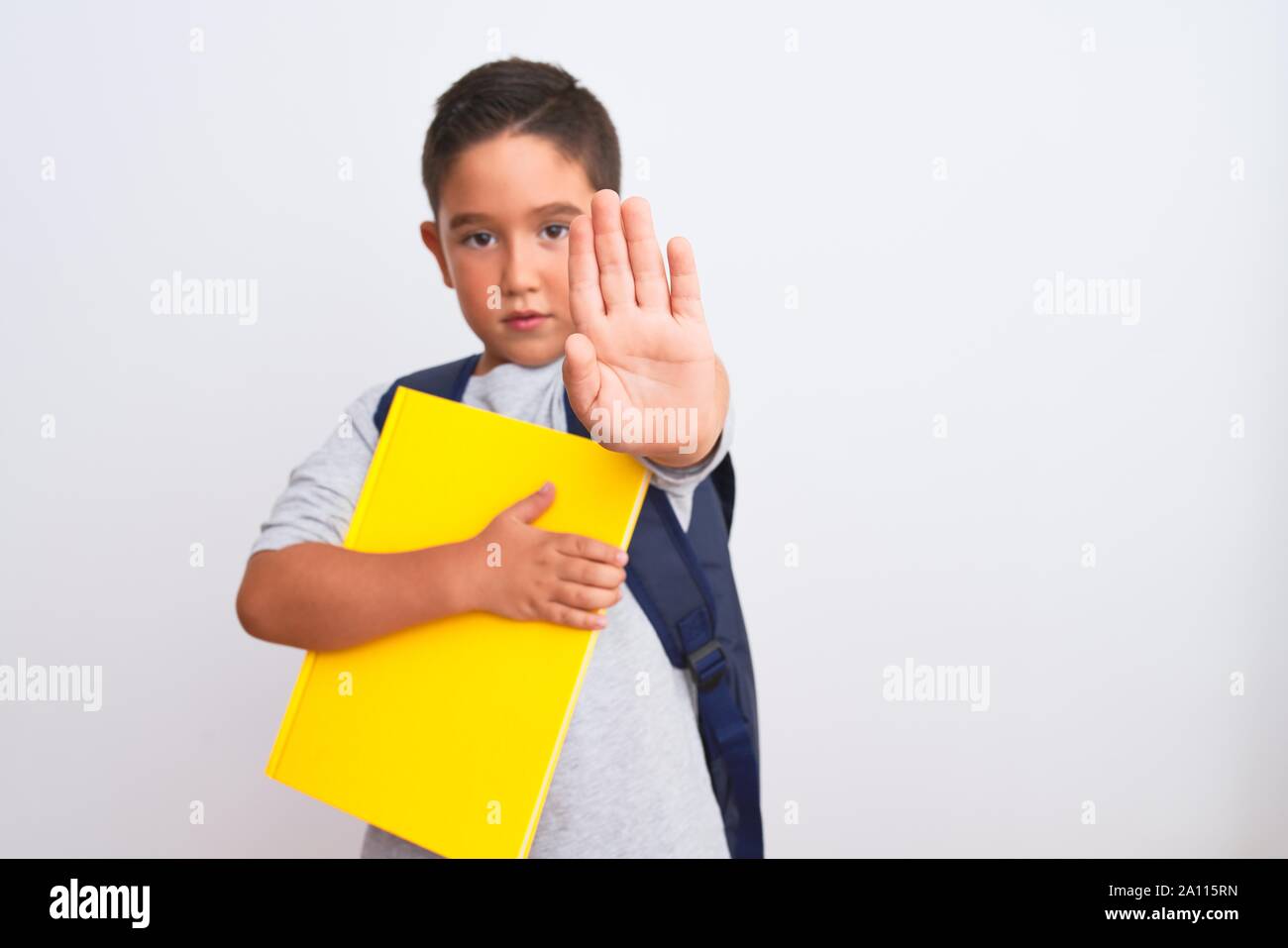 Beautiful student kid boy wearing backpack holding book over isolated ...