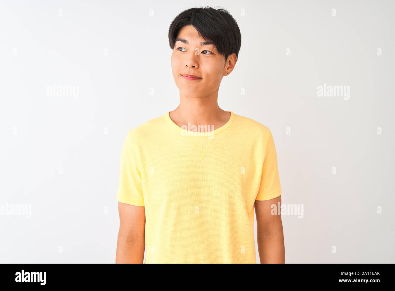 Chinese man wearing yellow casual t-shirt standing over isolated white ...