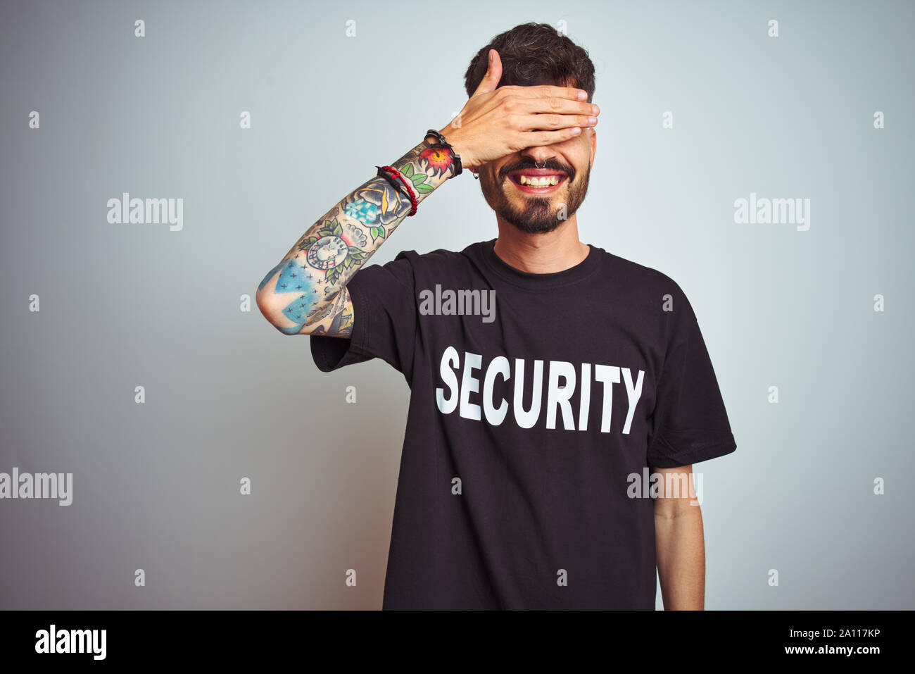 Young safeguard man with tattoo wering security uniform over isolated ...