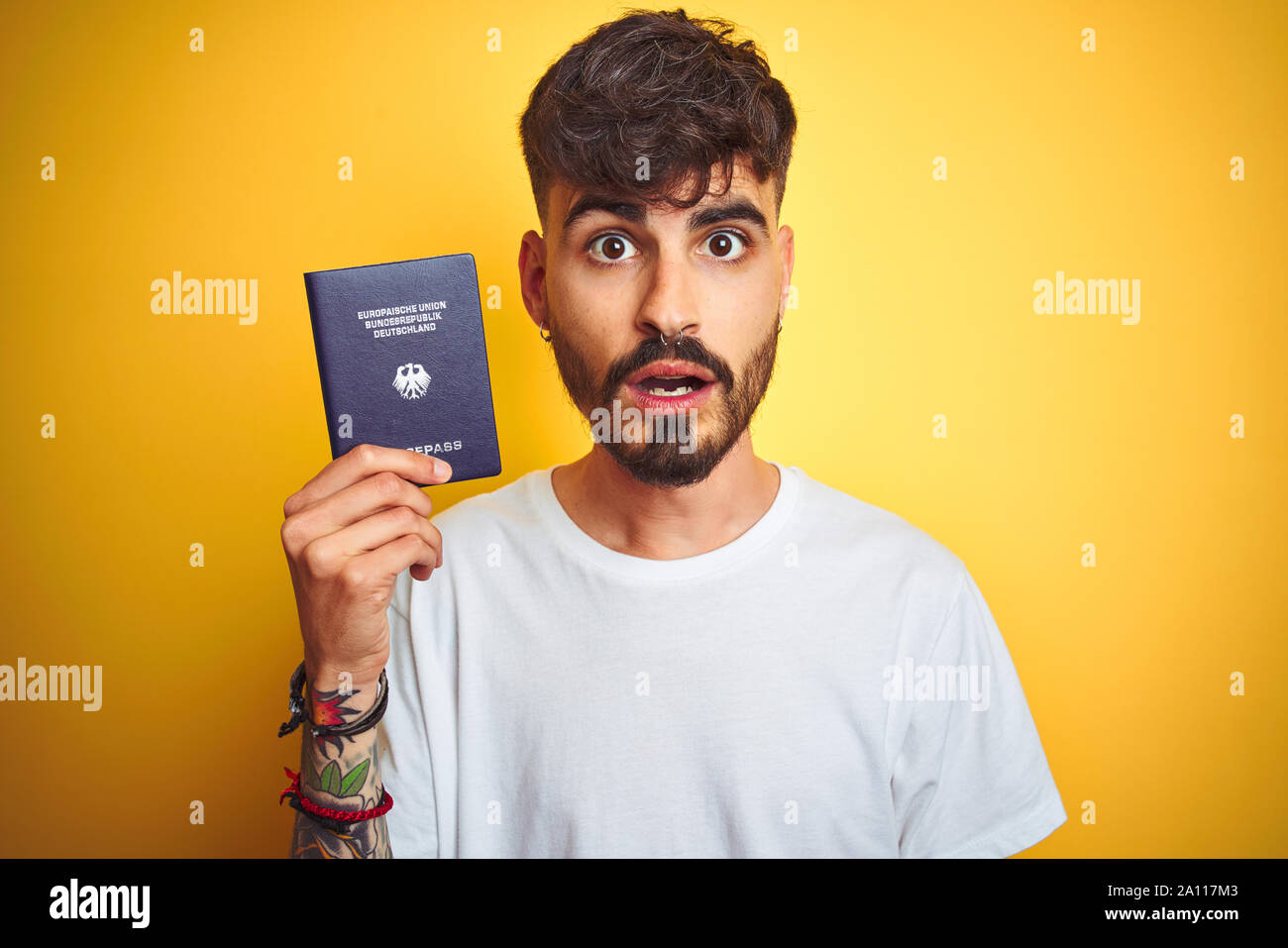 Young man with tattoo wearing German Germany passport over isolated ...