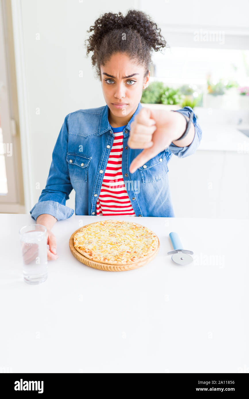 Young african american woman eating homemade cheese pizza with angry ...
