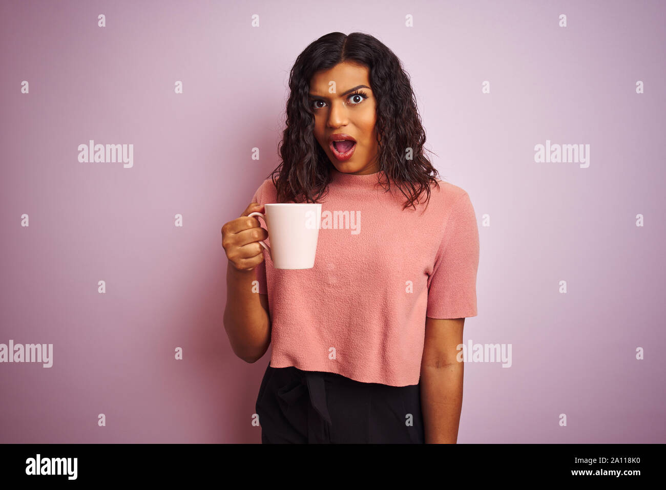 Transsexual transgender woman drinking cup of coffee over isolated pink ...