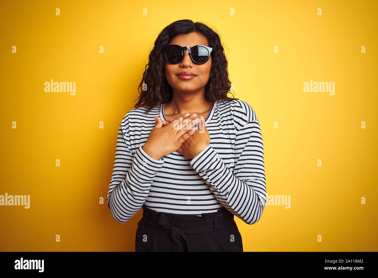 Transsexual transgender woman wearing sunglasses over isolated yellow ...