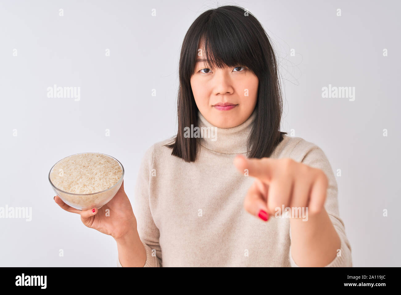 Young beautiful Chinese woman holding bowl with rice over isolated ...
