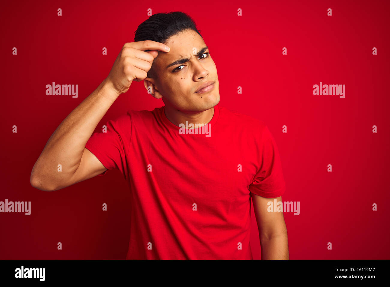 Young brazilian man wearing t-shirt standing over isolated red ...