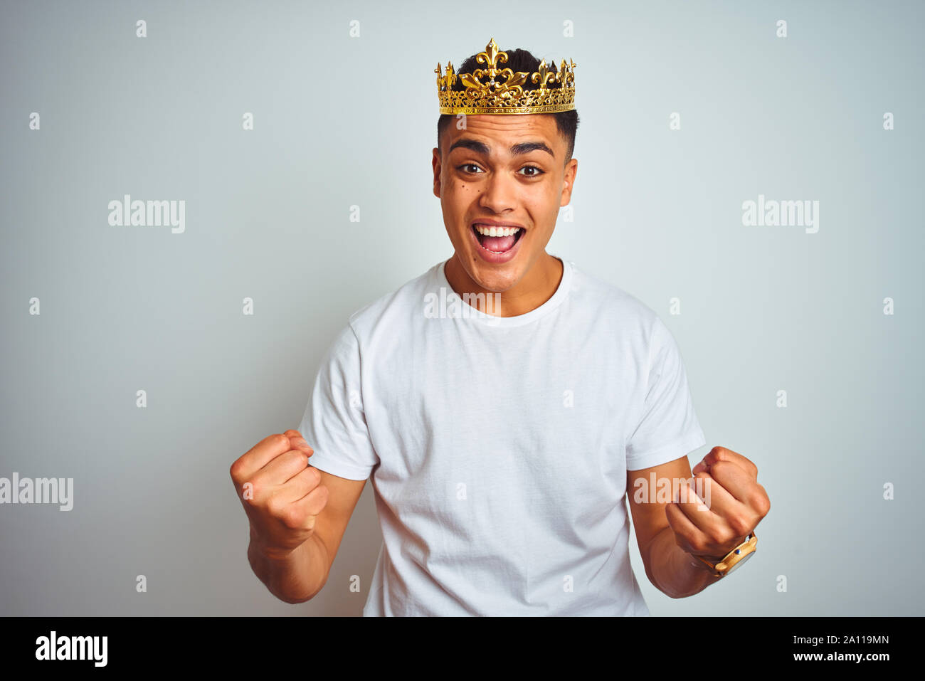 Young brazilian man wearing king crown standing over isolated white ...