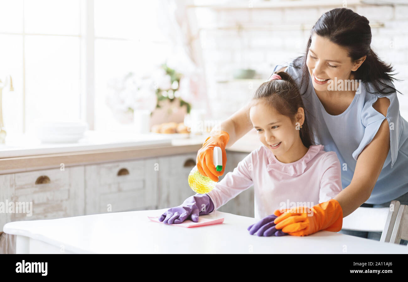 Caring mom teaching daughter how to clean table with detergent Stock ...