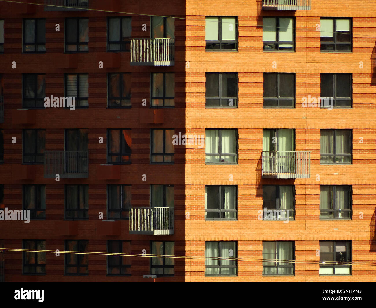 Corner of a house with Windows and balconies. One side is illuminated ...