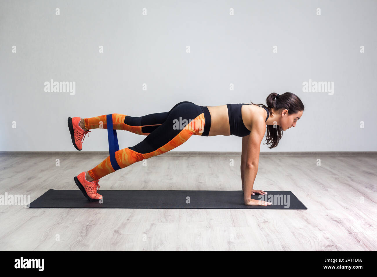 Side view portrait of young muscular woman wearing black top and orange ...