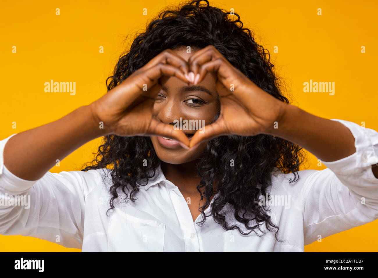 Cheerful african young woman shaping hands as heart on camera Stock ...