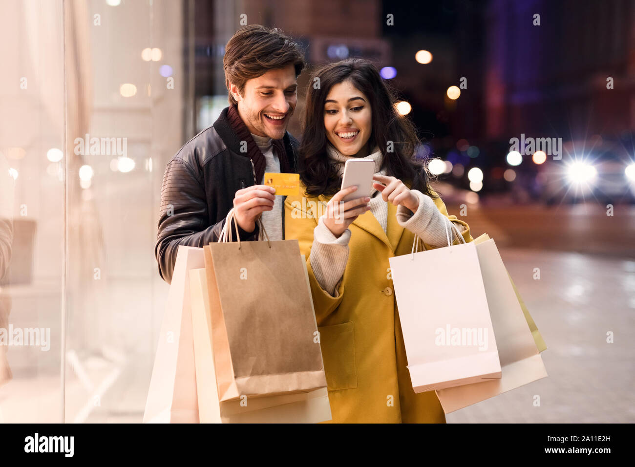 Consumerism concept. Happy couple checking cellphone outdoors Stock ...