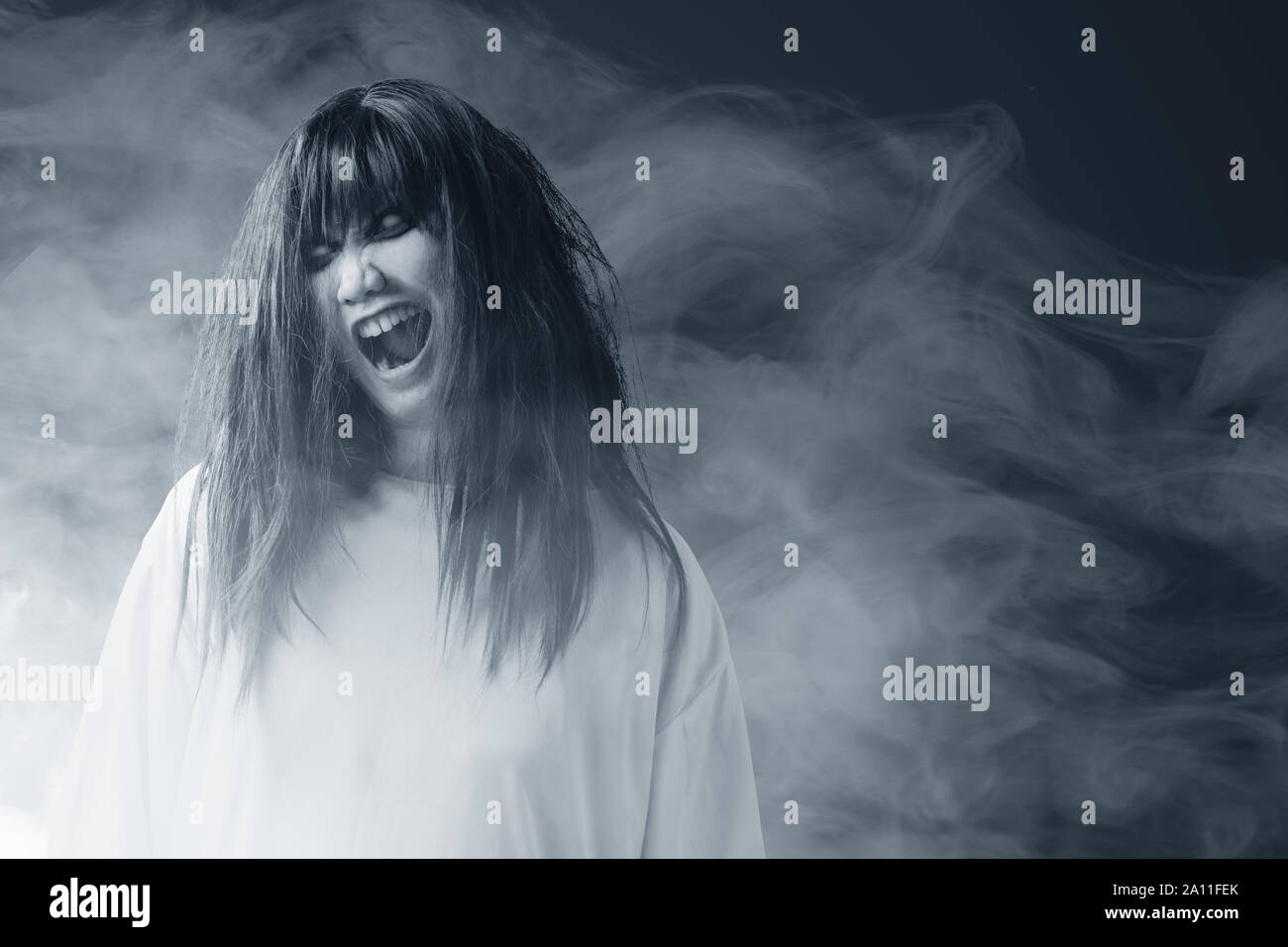 Scary ghost woman with blood and dirty face standing amid the dark fog ...