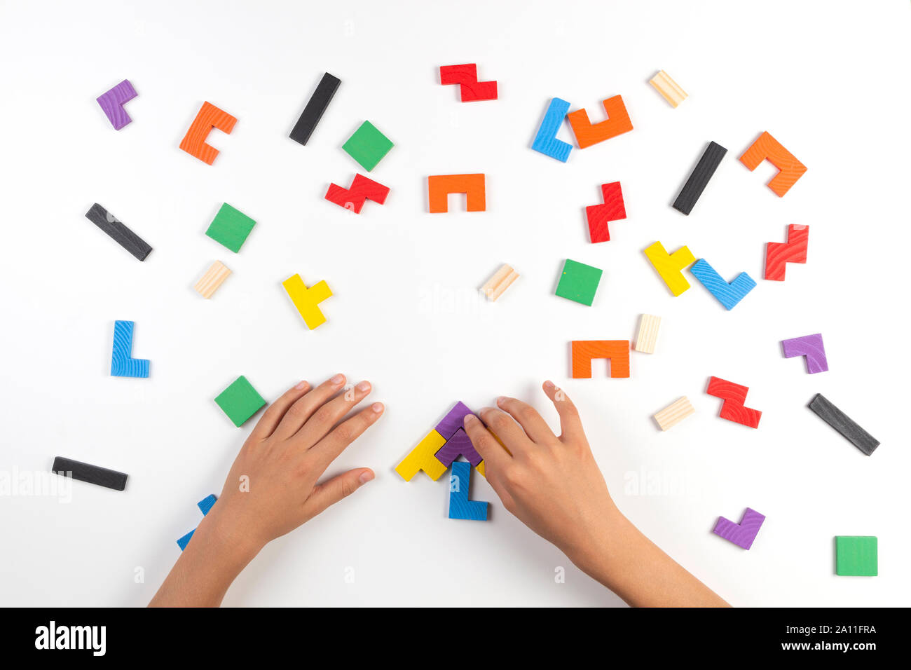 Kid hand playing with different colorful shapes wooden blocks on white ...