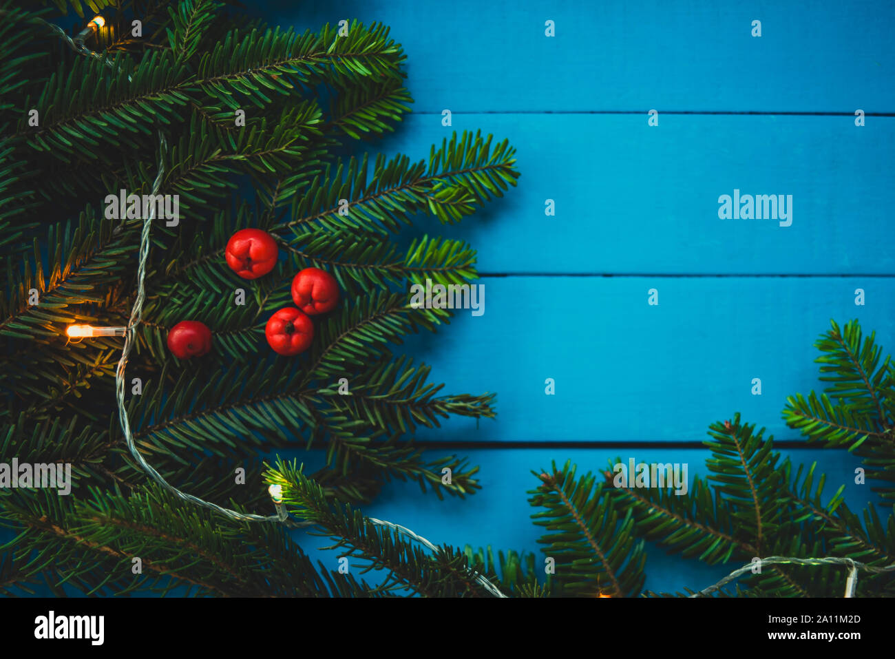 Evergreen branch with red berries on blue boards Stock Photo - Alamy
