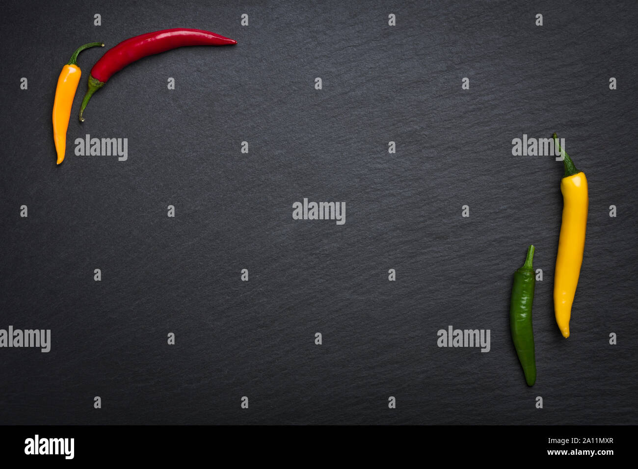 Four chili peppers isolated on slate stone Stock Photo - Alamy