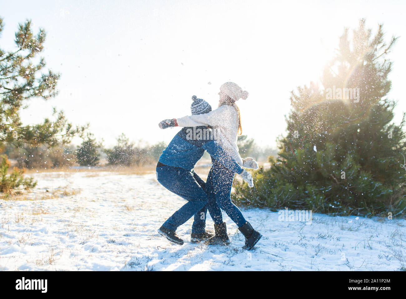 Loving couple play snowballs in winter in the forest. Throw each other ...