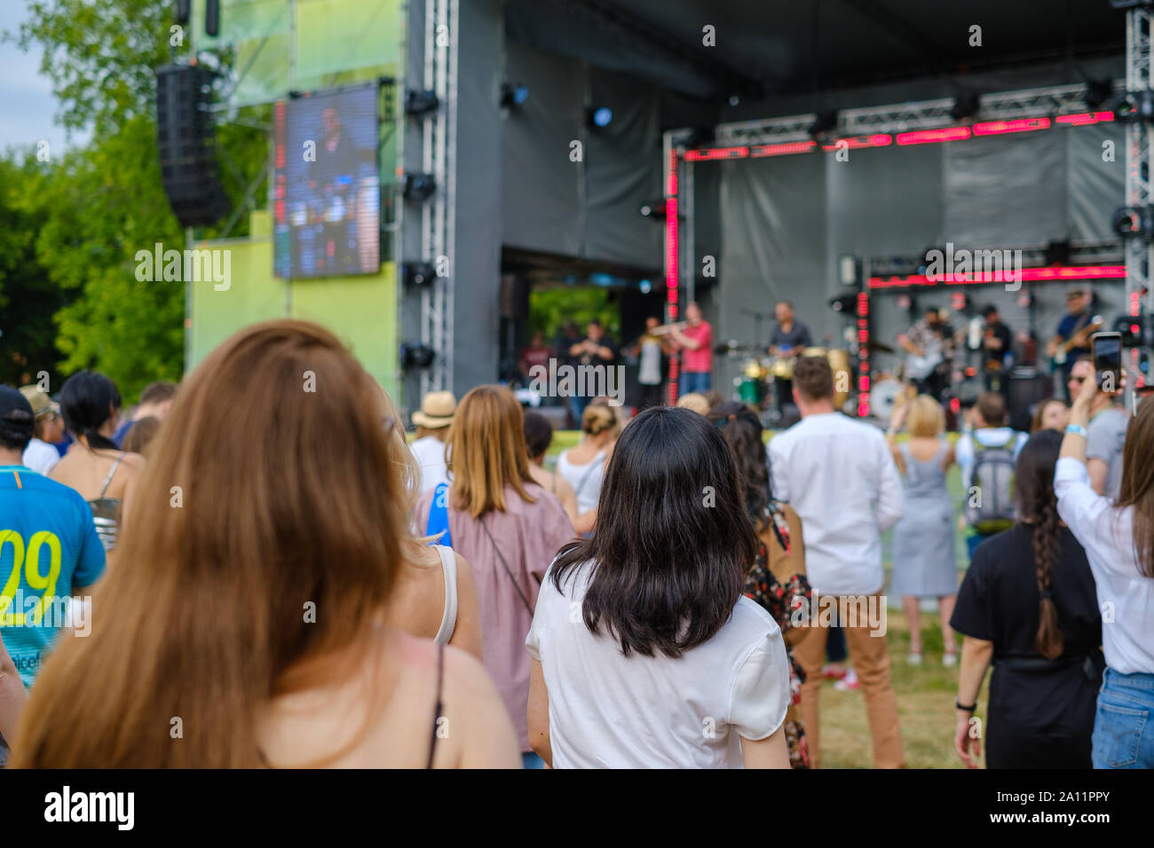 Girls friends watching concert at open air music festival, rear view ...