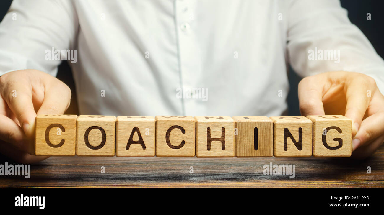 Wooden blocks with the word Coaching in the hands of a man. Self ...