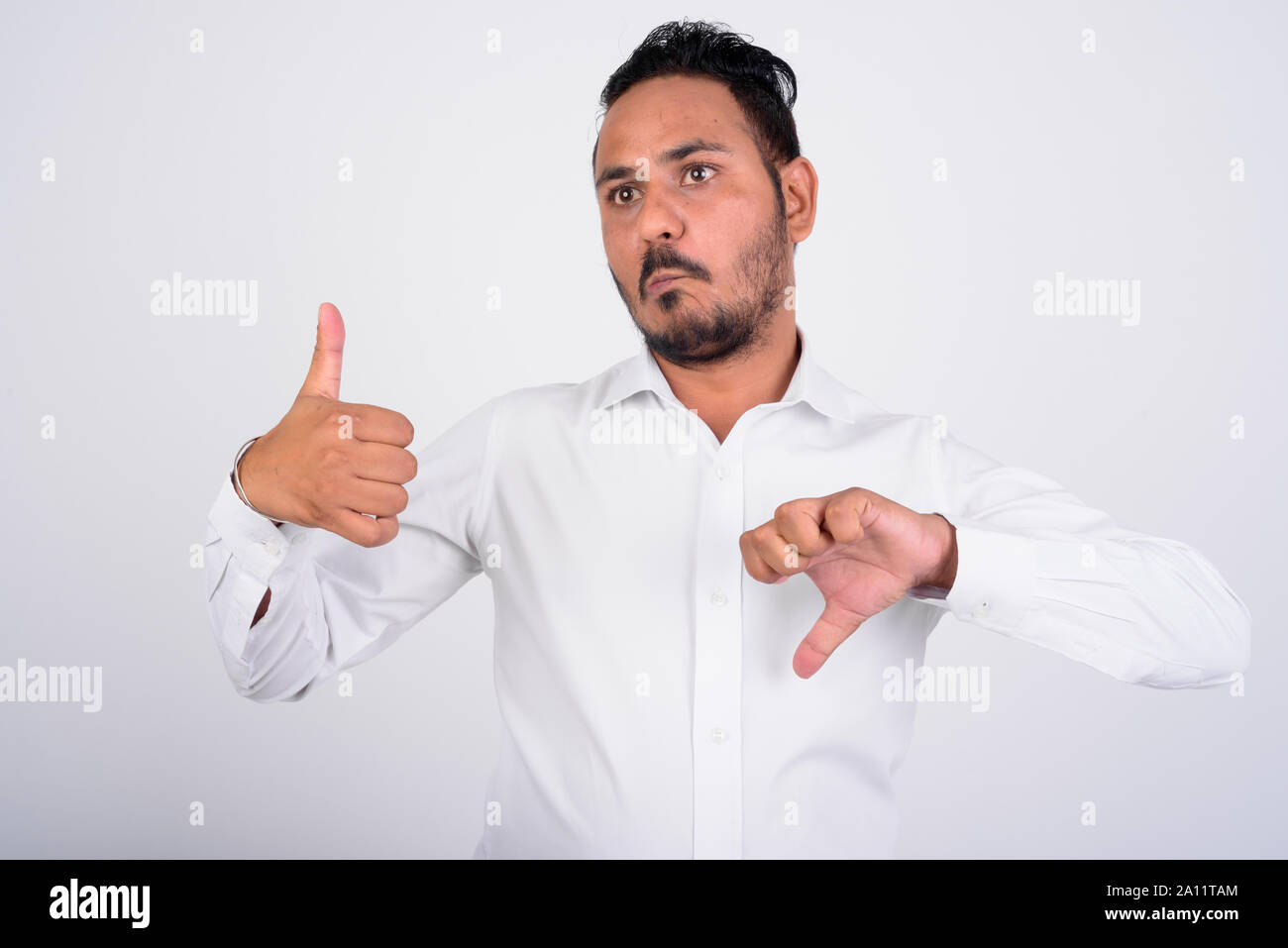 Confused bearded Indian businessman choosing between thumbs up and ...