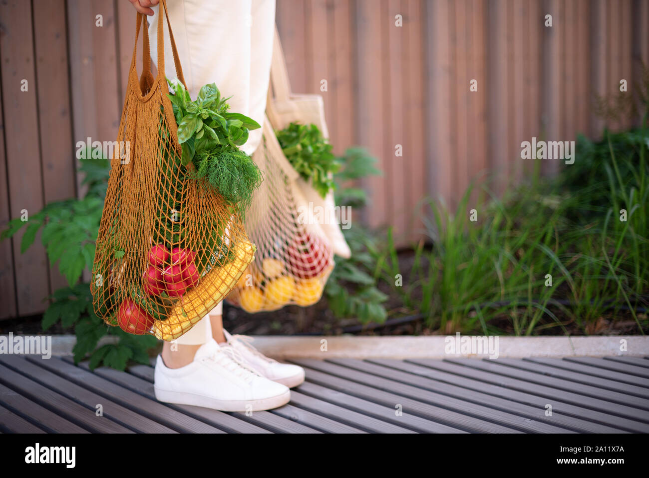 Girl holding mesh shopping bag and cotton shopper with vegetables ...