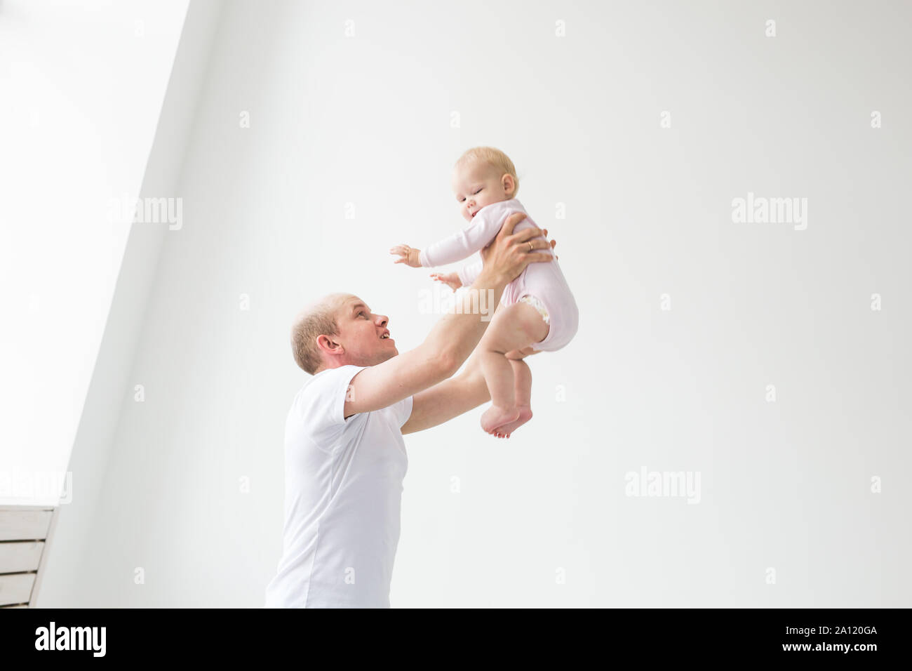 Happy young father lifting cute baby up high in air, spending and ...