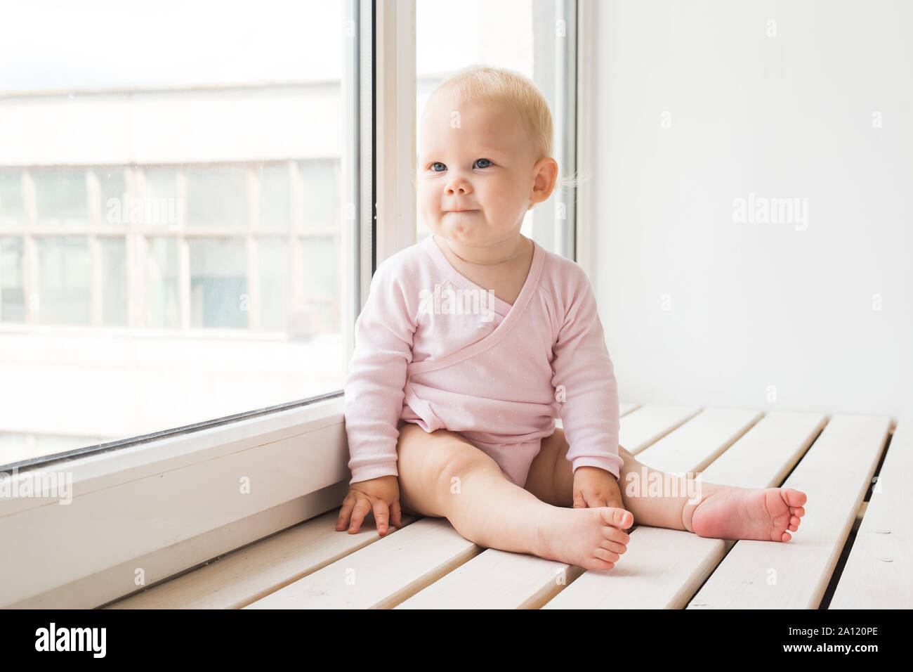 Childhood, family and infant concept - Little baby girl on windowsill ...