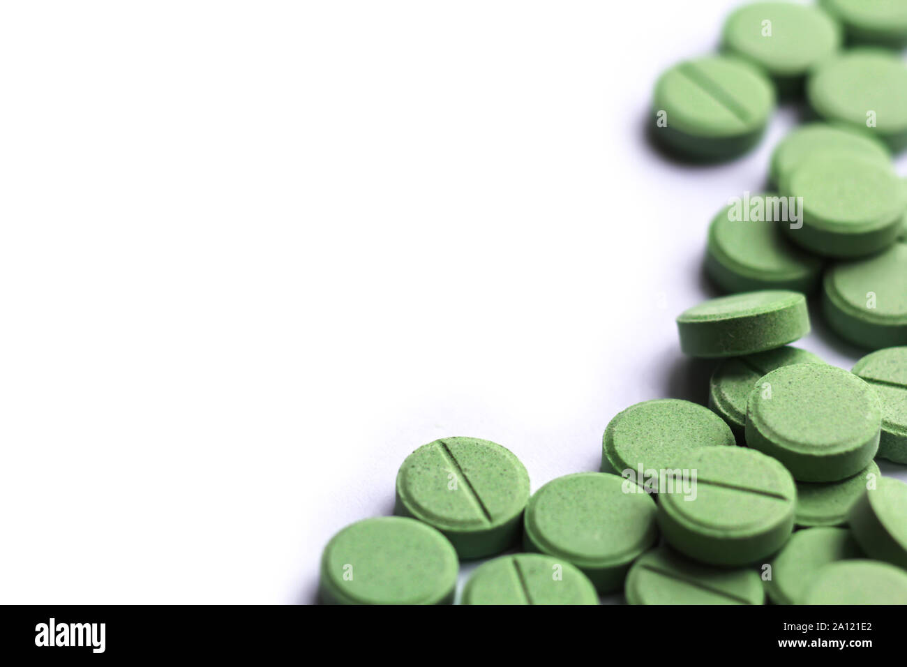 Heap of scattered mint green color medical pills tablets on white ...