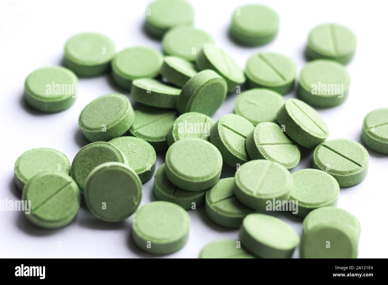 Heap of scattered mint green color medical pills tablets on white ...