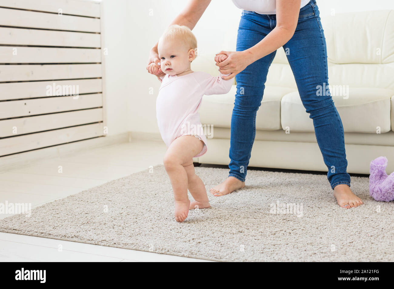 Little baby girl first steps with the help of mom Stock Photo - Alamy