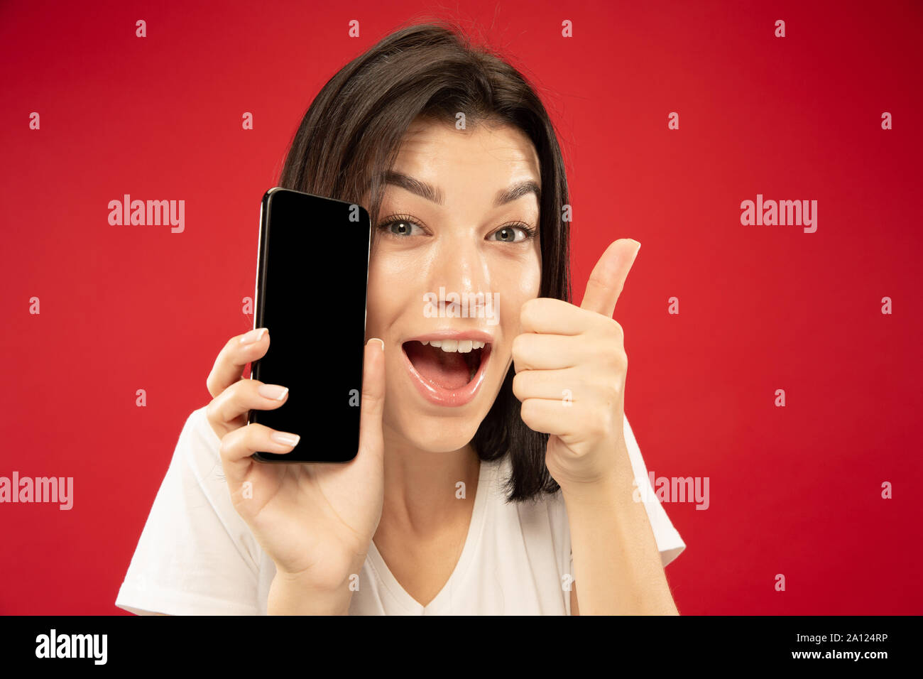 Caucasian young woman's close up portrait on red studio background ...
