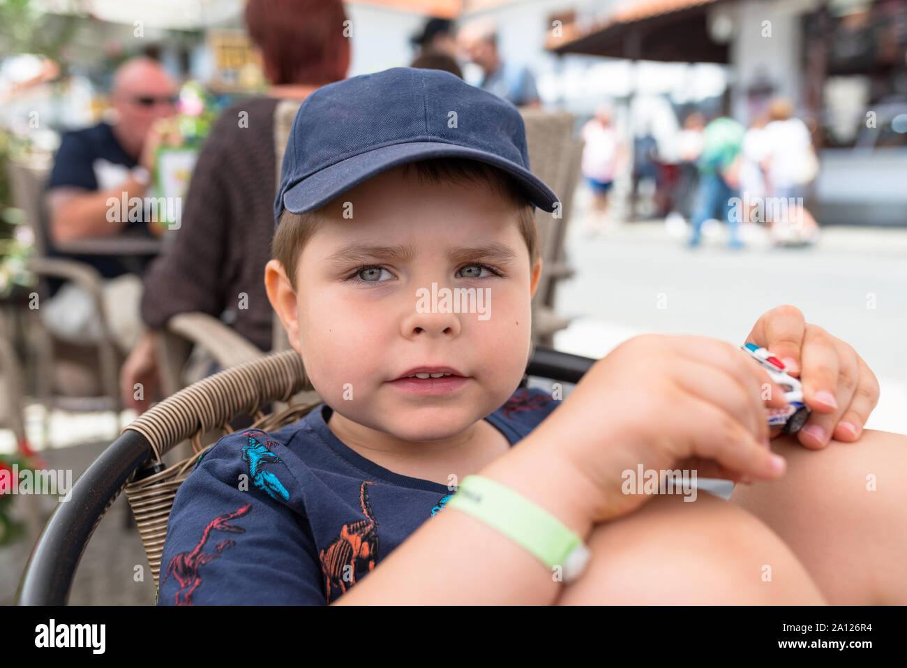 Five-year cute boy in a navy blue baseball cap sitting on a wicker ...