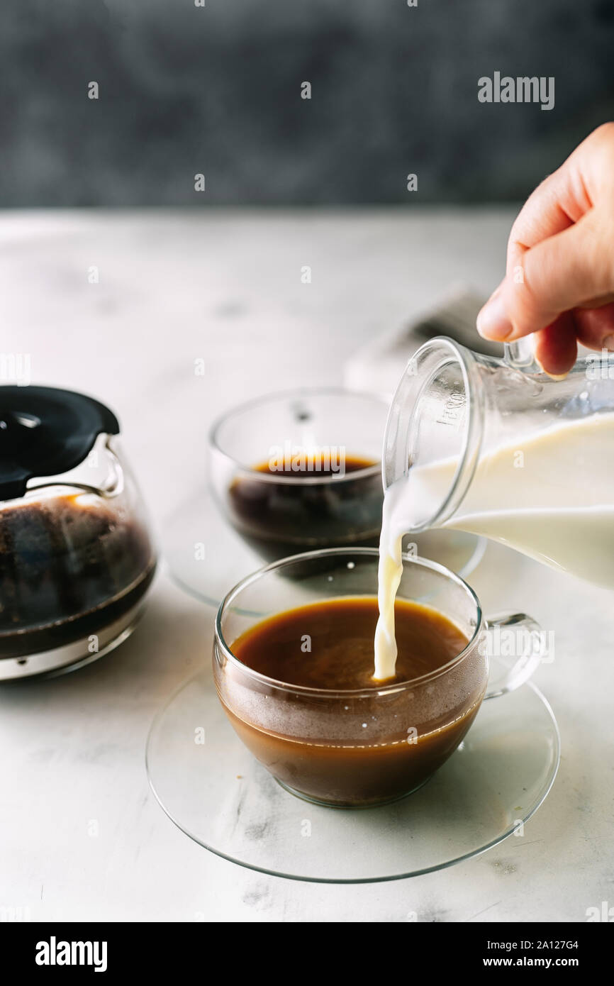 Morning coffee concept. Pouring a milk into morning cup of coffee Stock ...