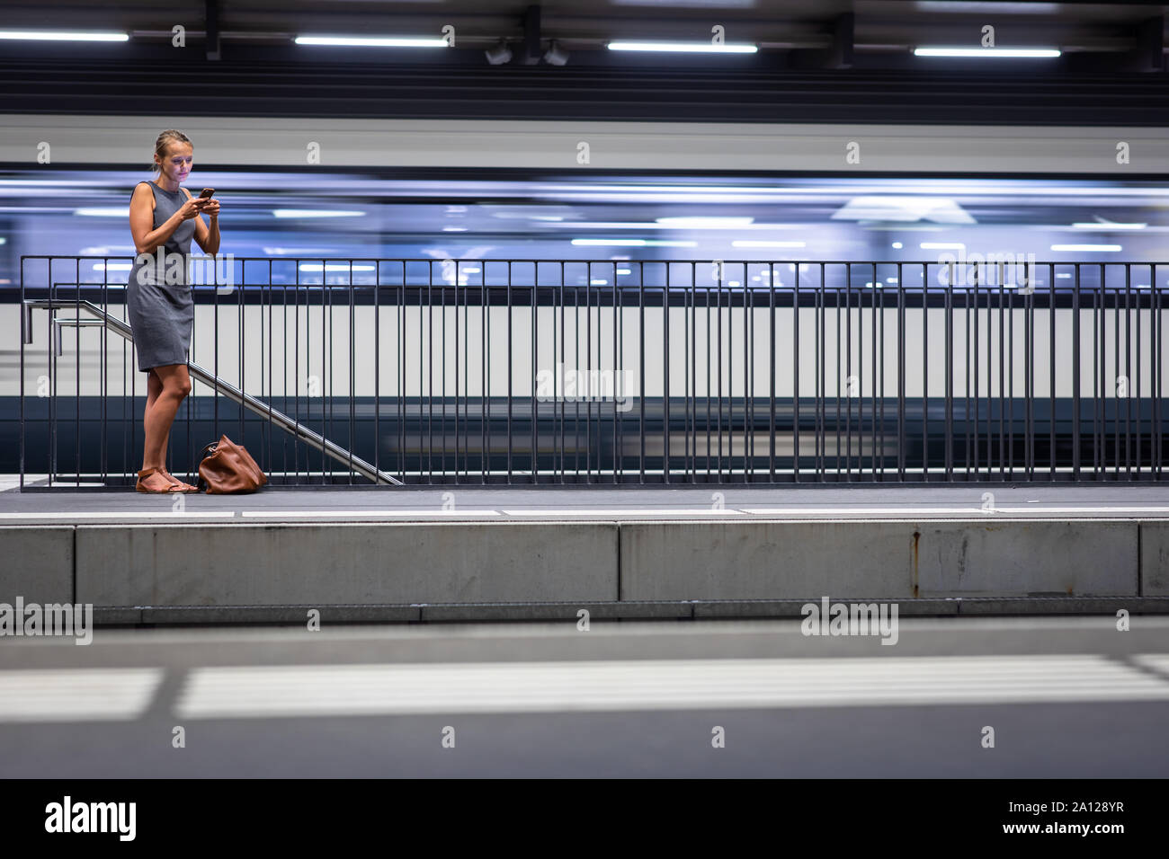 Pretty, young female commuter waiting for her daily train in a modern ...