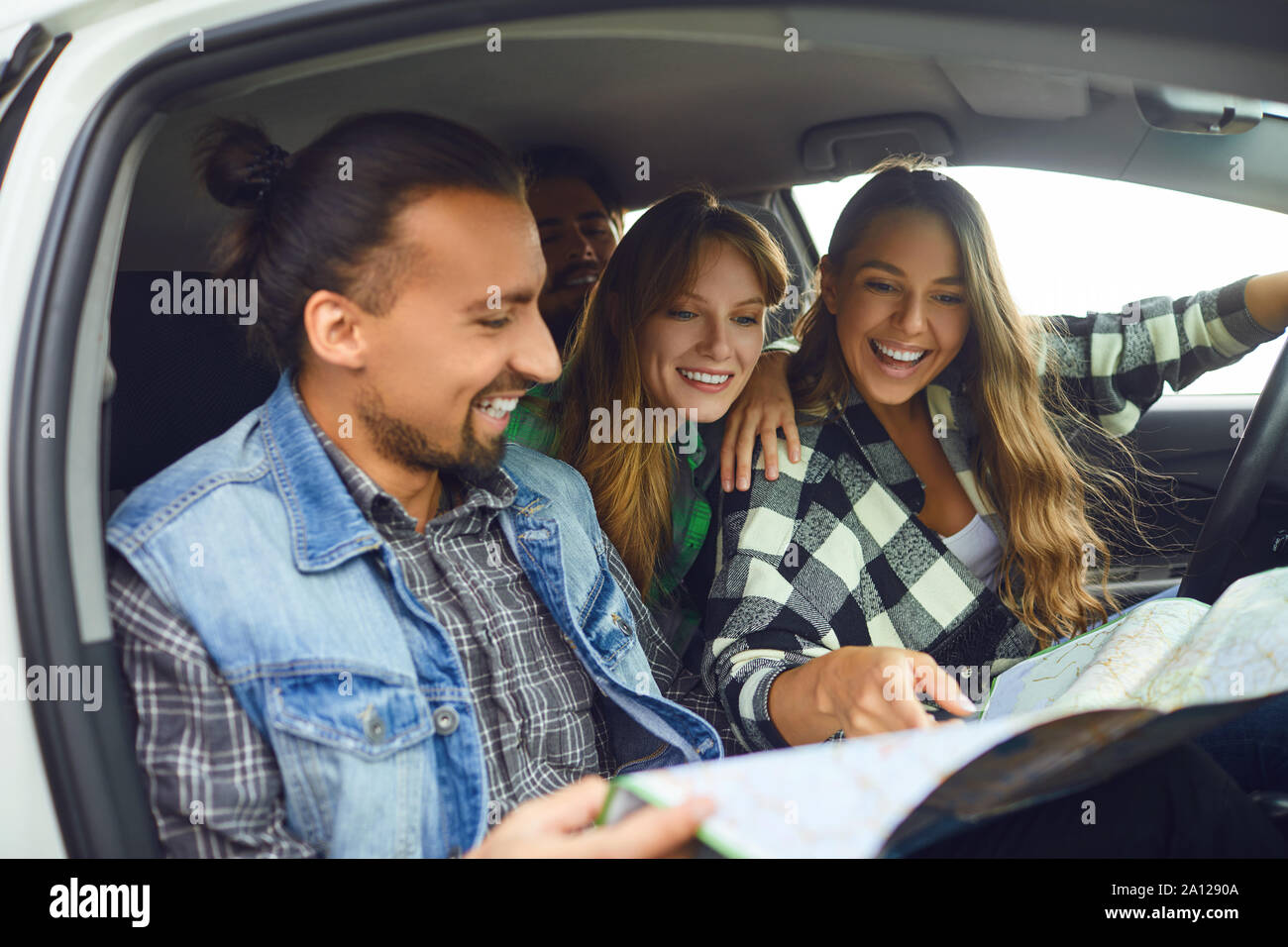 A group of friends choose the route on the map ride in the car Stock ...