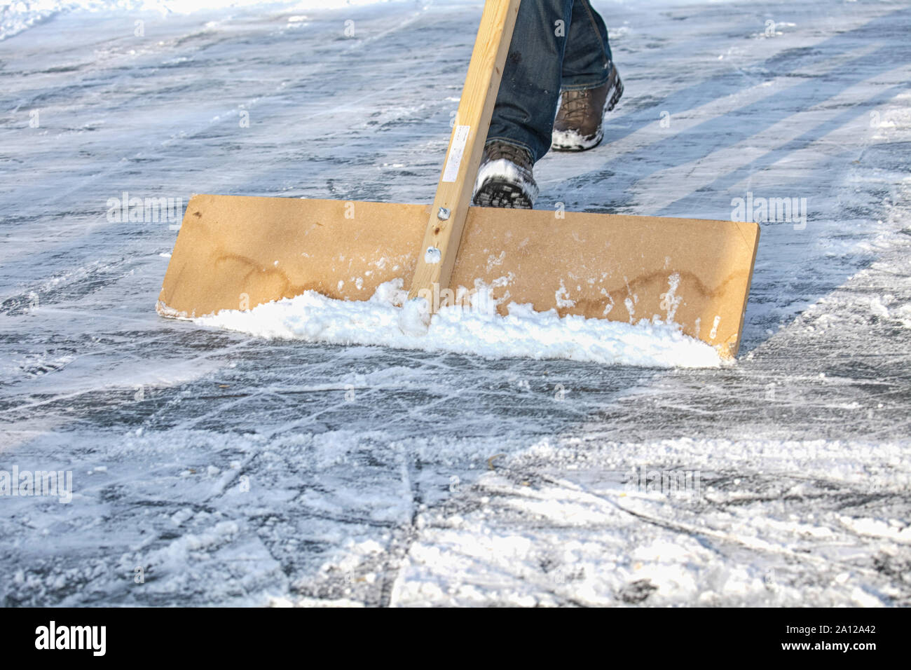 Shoveling snow with wooden shovel from ice for speed ice skating with ...