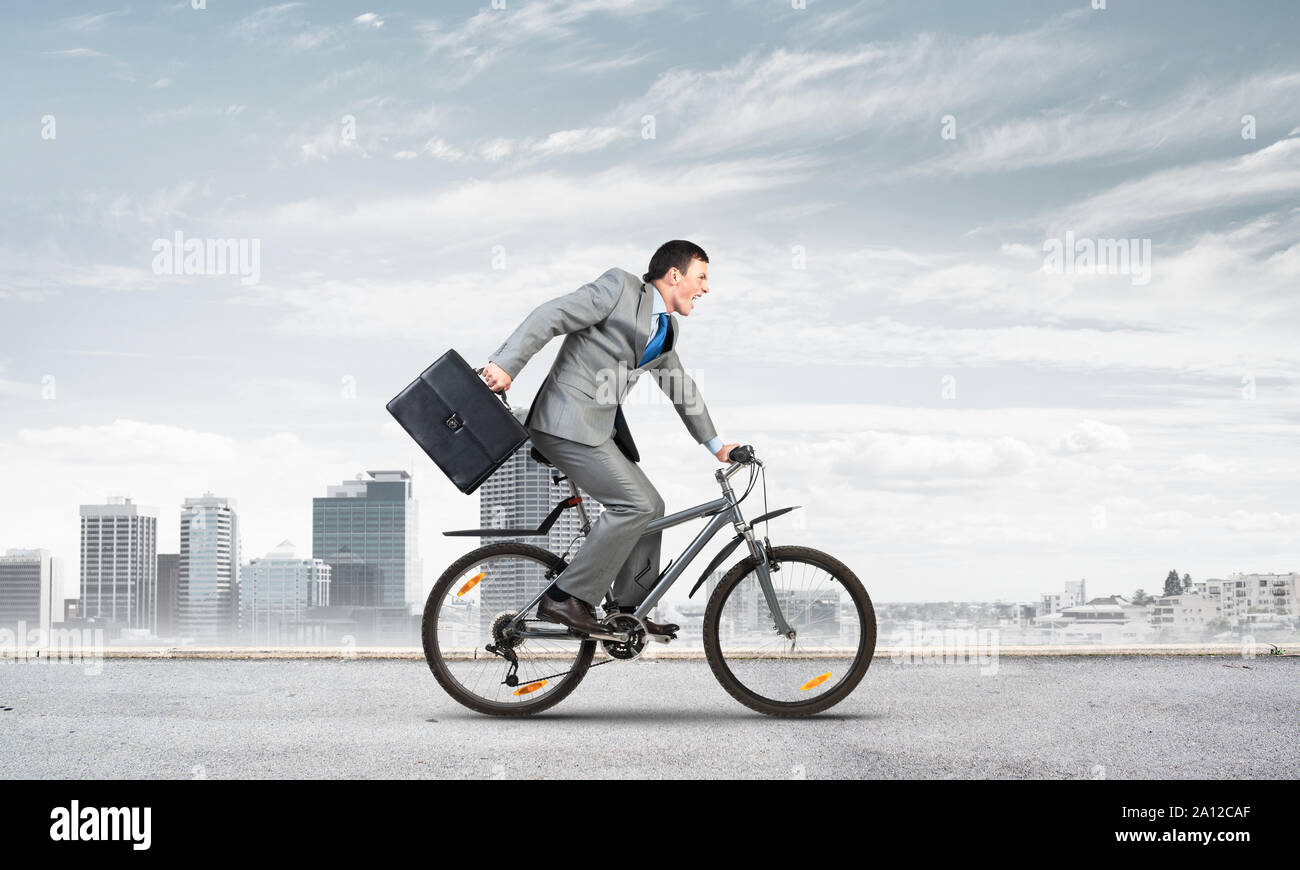 Young man riding bicycle on highway. Businessman on bike hurry to work ...