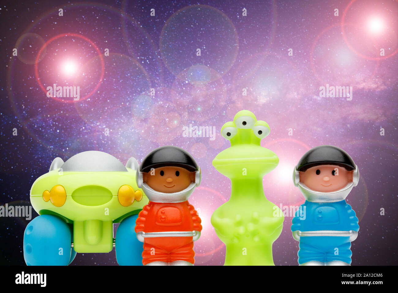 Two toy spacemen and an alien in a line with a stary sky in the ...