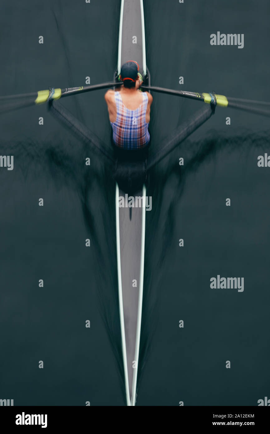 Overhead view of an oarsman in a single scull boat on calm water mid ...