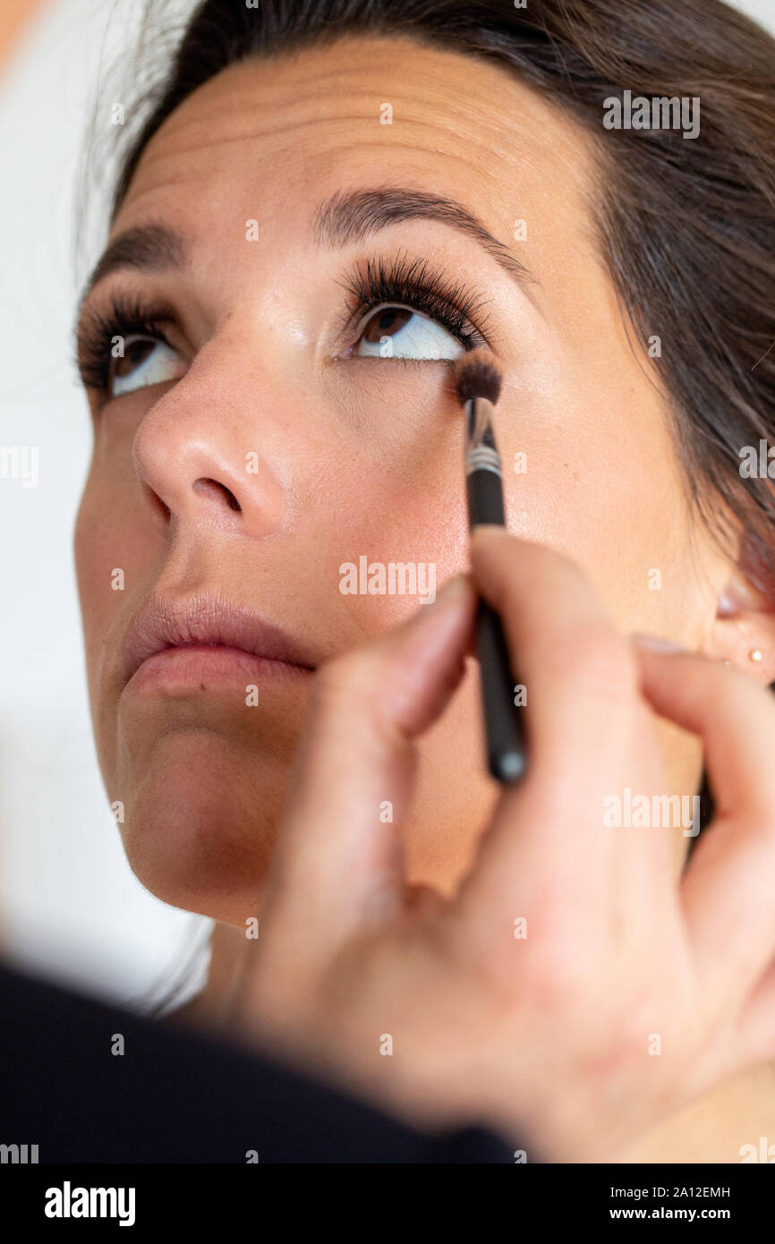 A professional make up artist at work, creating a look for a young ...