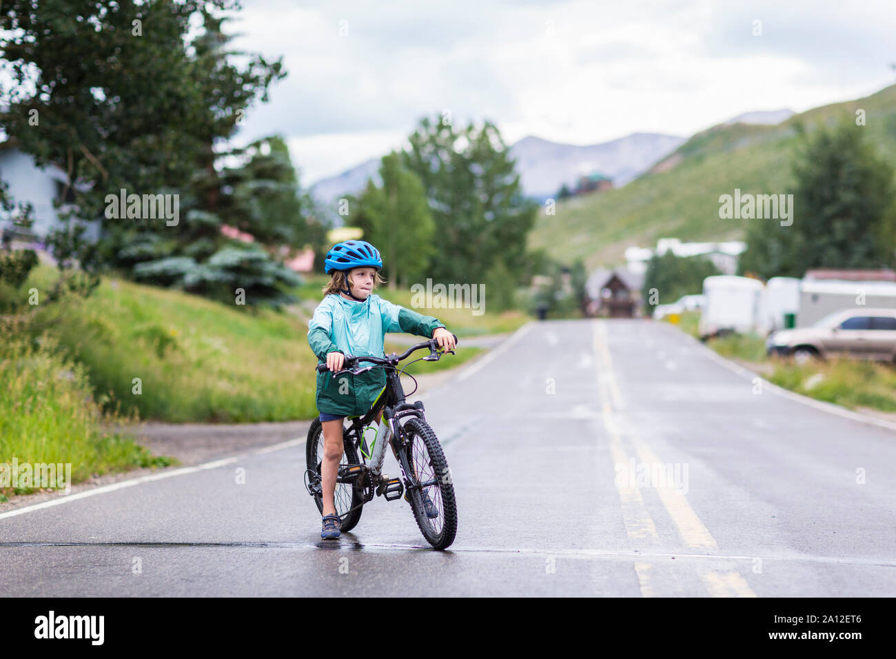 5 year old boy straddling his mountain bike on rainy road Stock Photo ...