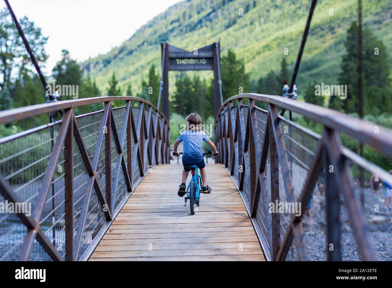 rear view of 5 year old boy on mountain crossing narrow bridge Stock ...