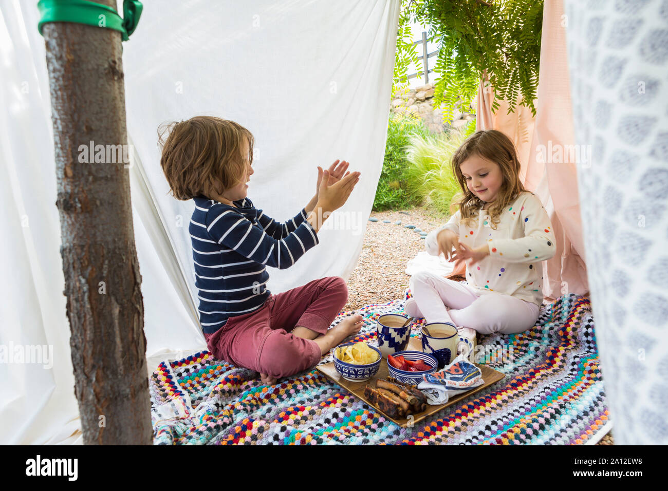 young boy and girl playing in outdoor improvised tent Stock Photo - Alamy