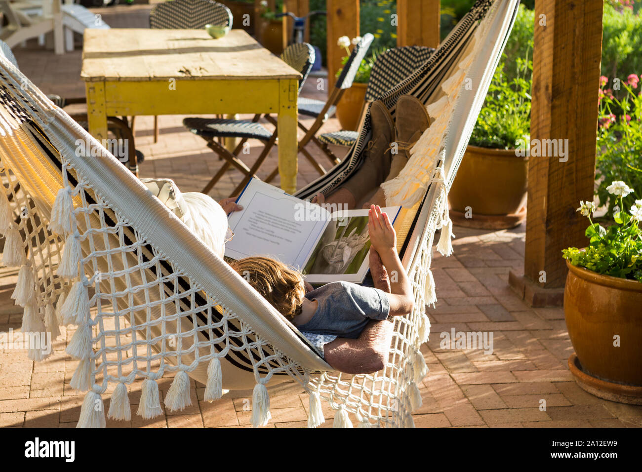 Two people lying in a hammock on a porch reading Stock Photo - Alamy